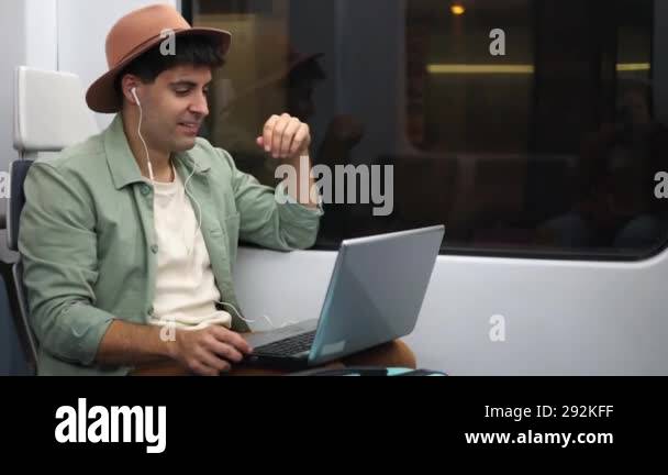 relaxed traveler wearing headphones, using their laptop while sitting ...