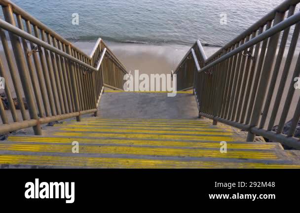 Straightforward view of beach stairs with yellow markings, leading to ...