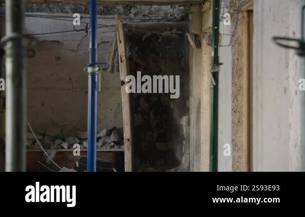 Workers dismantle broken concrete slabs amidst fire aftermath, exposing ...
