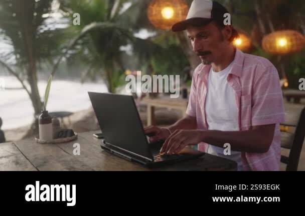 Male developer types script, creates software near palm trees, ocean ...