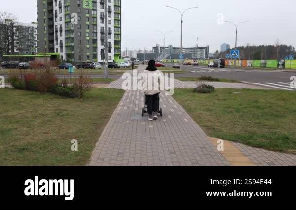 A parent takes a stroll along a designated walkway in an urban area ...
