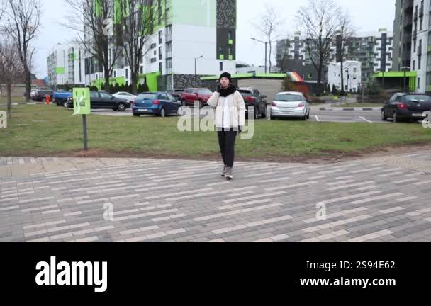 A woman dressed in a stylish outfit poses on a walkway surrounded by ...