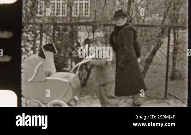 8mm shot of a little boy pushing a pram while walking with a woman ...