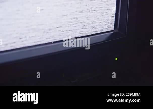A vintage CRT television screen displaying static noise with flickering ...