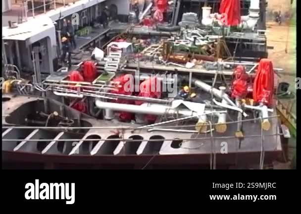 A shipyard work area buzzes with activity as numerous workers engage in ...