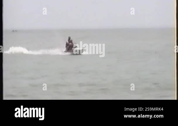 A father and son jet skiing together, racing across the water towards ...
