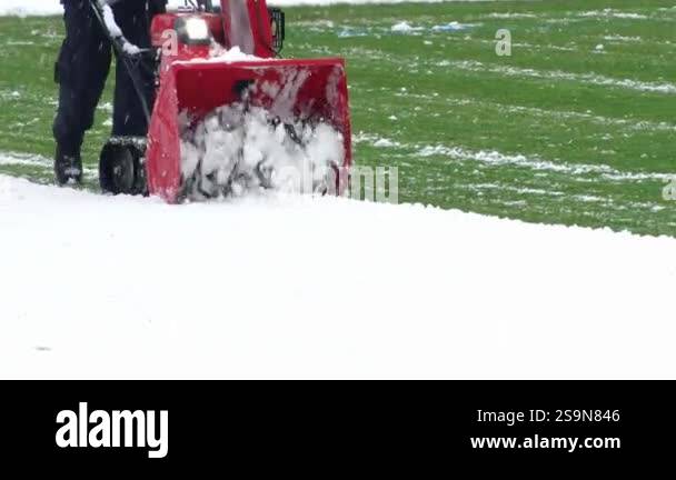 Skilled groundskeeper operating powerful snow blower across frosted ...