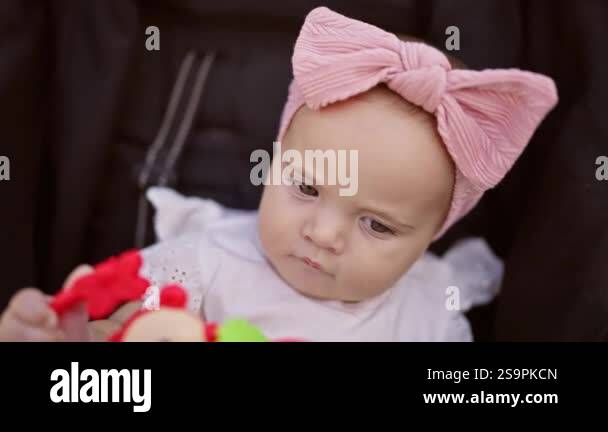 Adorable, serious-faced baby chilling in relaxation on a baby chair ...