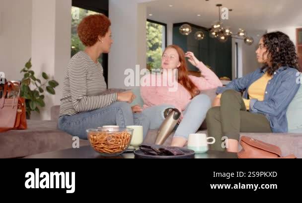 Chatting and relaxing, diverse female friends sitting on couch with ...