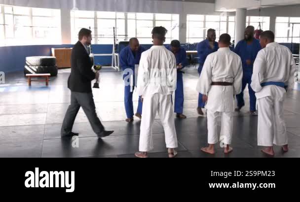 Celebrating victory, judo team in blue uniforms holding trophy in dojo ...