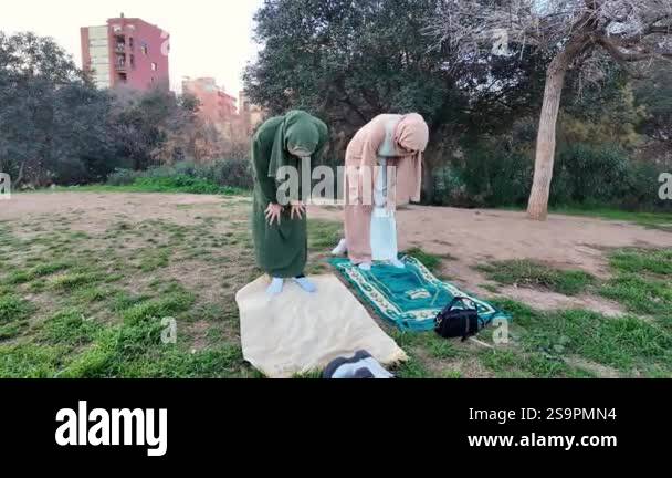 Two devout muslim women performing salat prayer, sitting on prayer rugs ...