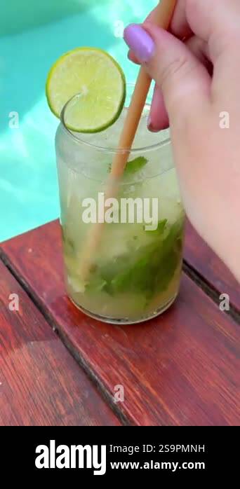 Chilled glass of iced mint tea with lemon slice and straw offers refreshing summer cool-down ...