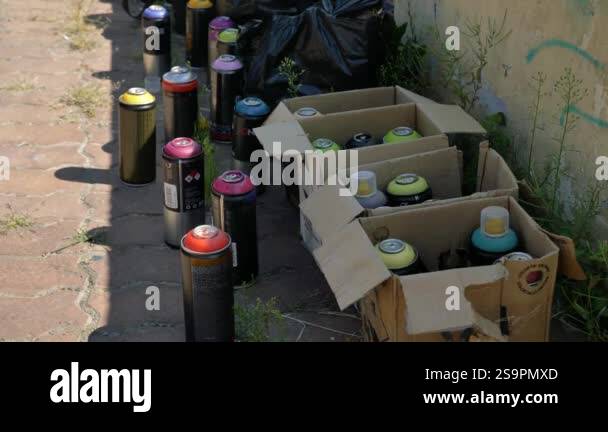Several used multi-colored spray paint cans stacked near a wall ...