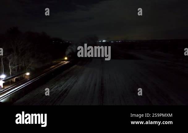 A steam train makes its way through a snow-covered landscape under a ...