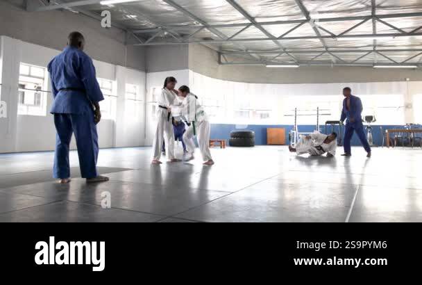 Practicing judo, students sparring in dojo with instructor supervising ...