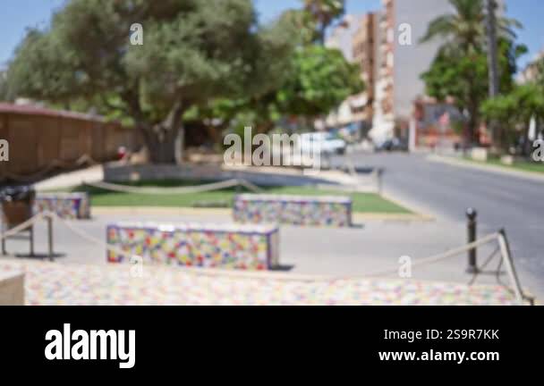 Outdoor urban scene with colorful benches, mosaic art, trees, blurred ...