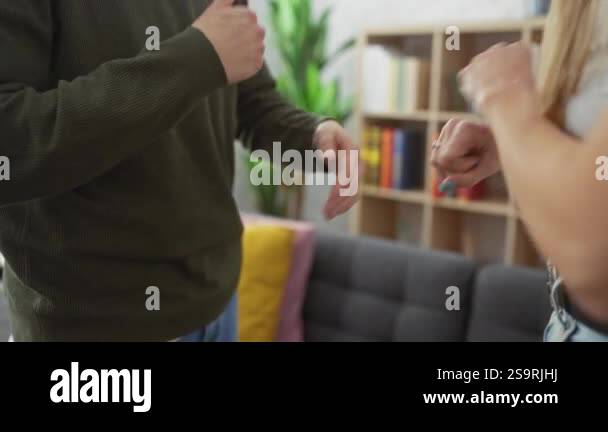A couple communicates through hand gestures in a cozy living room ...