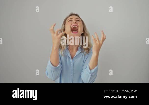 Young blonde woman in furious rage, arms raised, shouting and yelling ...