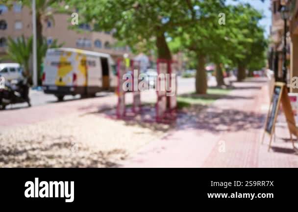 Blurred outdoor street scene with defocused trees, van, and urban bokeh ...