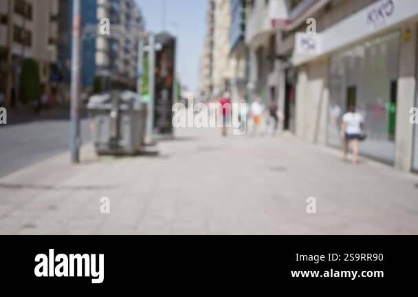 Blurred people walking on a bright sunny day in a bustling urban street ...