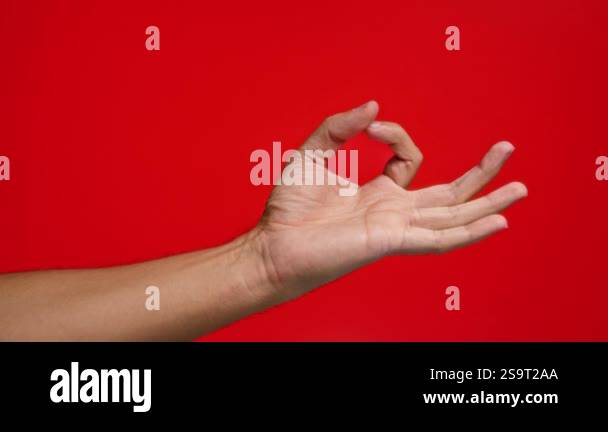 Man hand making an ok gesture against a vibrant red background ...
