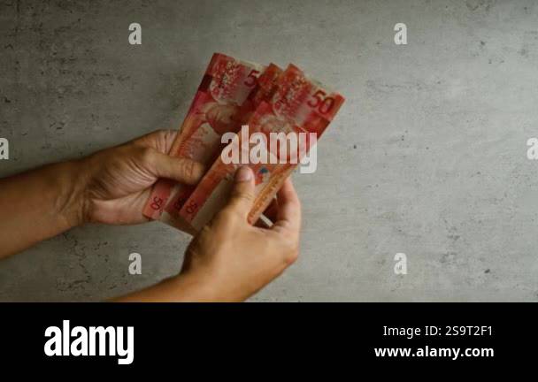 Man holding and counting 50 philippine peso bills with both hands ...