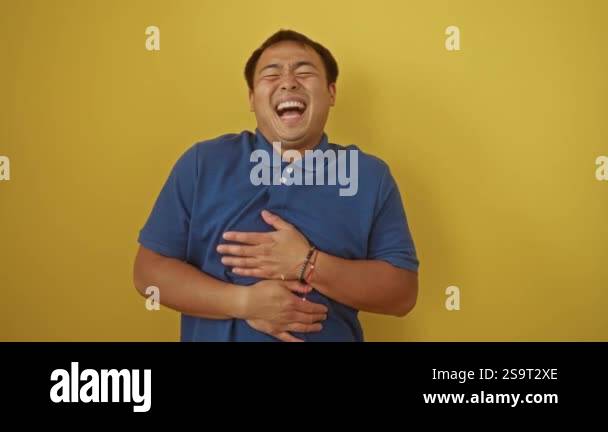 Laughing, young chinese man standing, smiling and laughing hard out ...