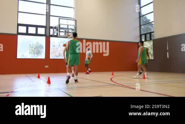 Basketball players practicing drills in gym with coach, focusing on ...