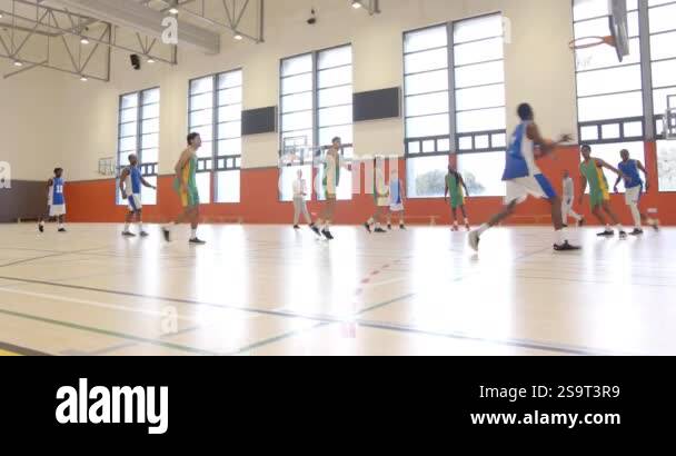 Playing basketball in school gym, students in uniforms practicing game ...