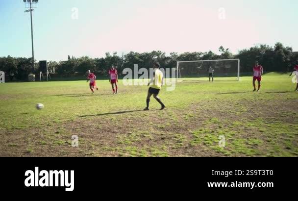 Playing soccer on field, two men running towards goal, goalkeeper ready ...
