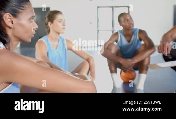 Basketball coach explaining strategy on clipboard to female players in ...