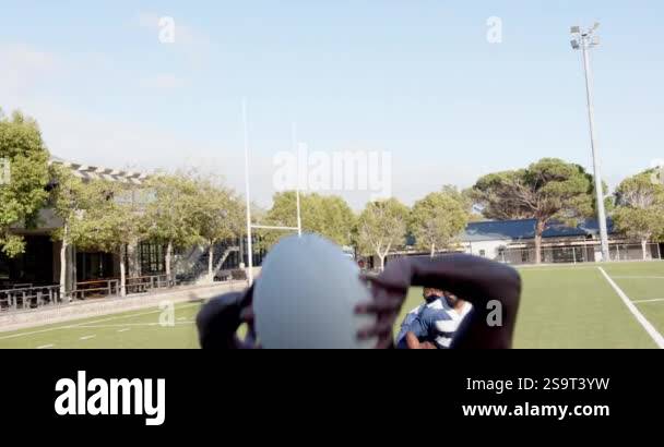 Playing rugby, african american men jumping to catch ball on field ...