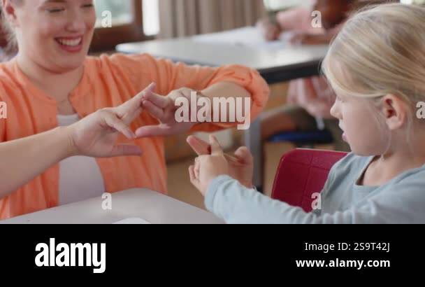 In school, female teacher and student practicing sign language together ...