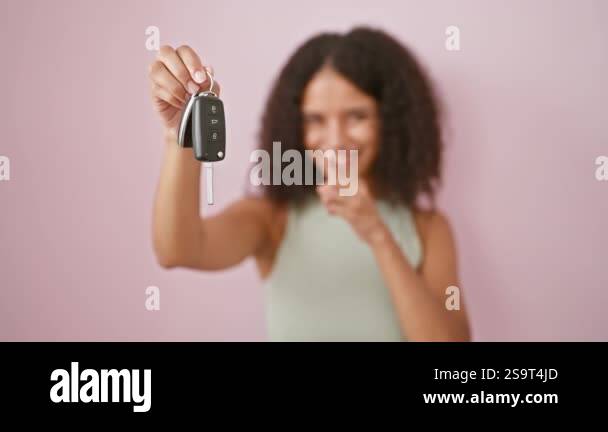 Cheerful young hispanic woman thrillingly holding up new car key ...
