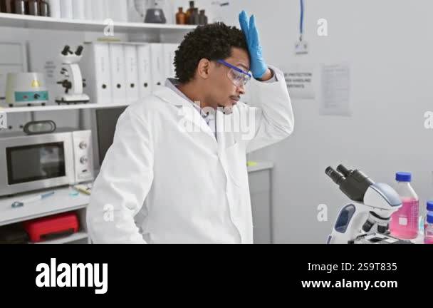 Young african-american man, a flustered scientist in safety glasses ...