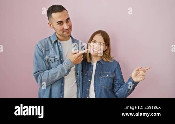 Beautiful couple in denim shirts, smiling and cheekily pointing to the ...