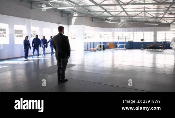 Practicing judo, students in uniforms standing in line in gym with ...