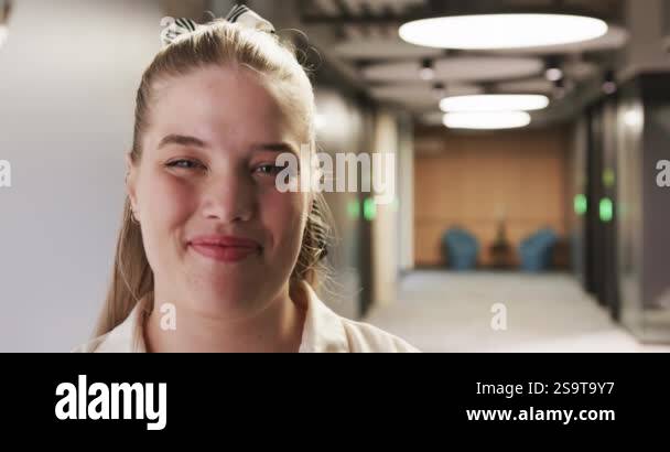 Expressing happiness and confidence, smiling woman in office hallway ...