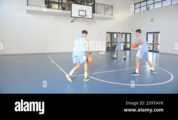 Basketball players practicing passing drills on indoor court, focused ...