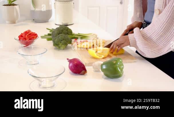 Woman chopping vegetables in kitchen, preparing fresh ingredients for ...