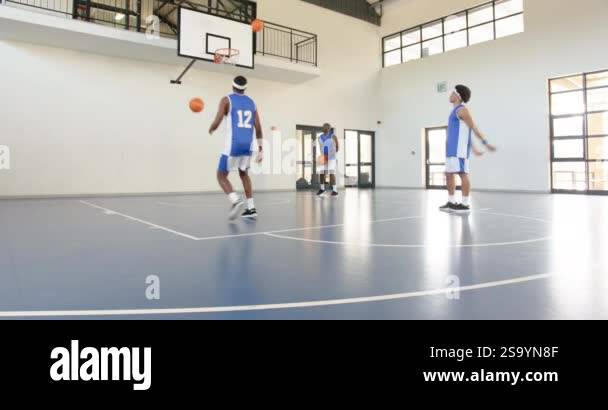 Basketball players practicing shots and dribbling on indoor court in ...