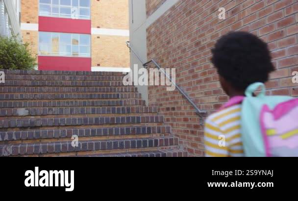 Walking up stairs, student with backpack heading to school building ...