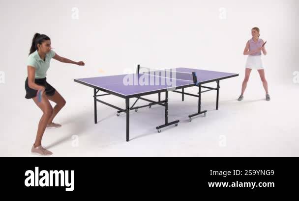 Playing table tennis, woman holding paddle and standing next to table ...