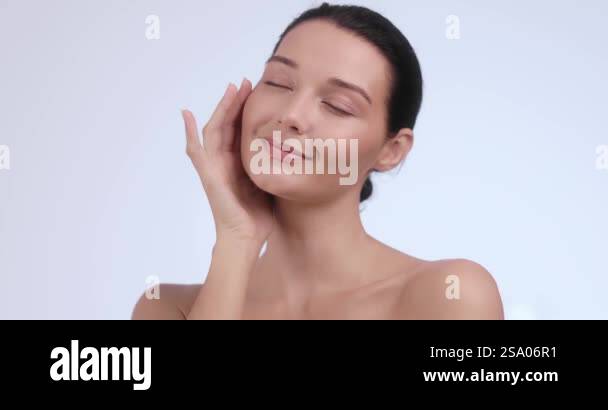 A beautiful woman with flawless skin gently touching her face and ...