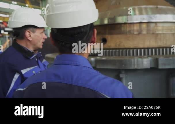 An industrial worker is attentively observing the operation of heavy ...