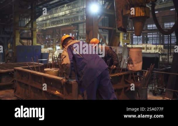 In a busy industrial setting, two focused workers exemplify strong ...