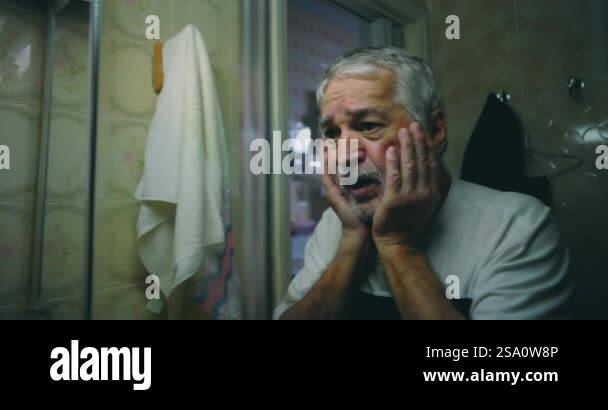 Elderly man overwhelmed with despair, hands clutching face, eyes wide ...