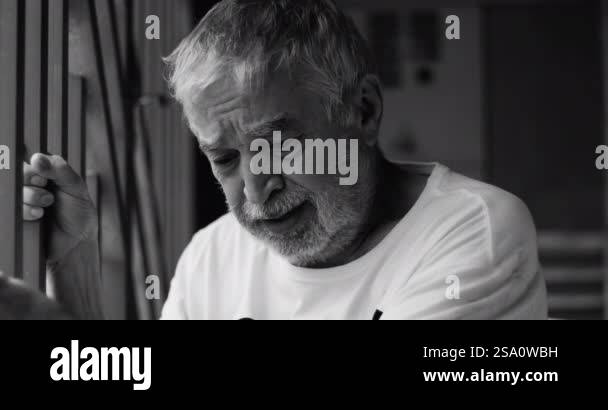 Elderly man in garage leaning on metal bars, crying in sorrow and ...
