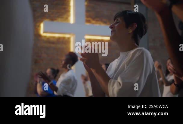 Woman clapping hands in worship among diverse group in church ...