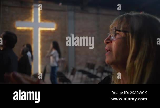 Arms raised in worship during a church service, glowing cross in ...